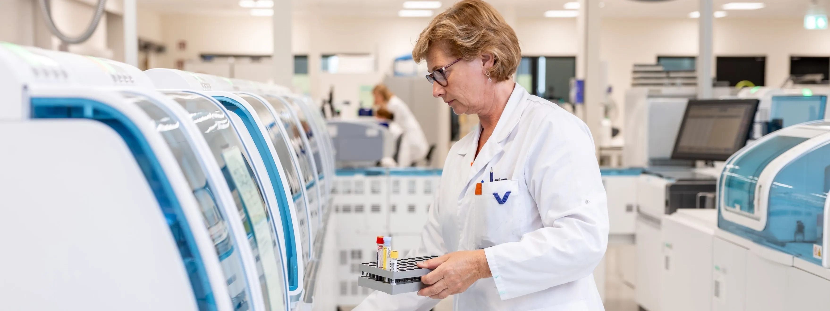 De header van de website. Medewerker lab aan machine.